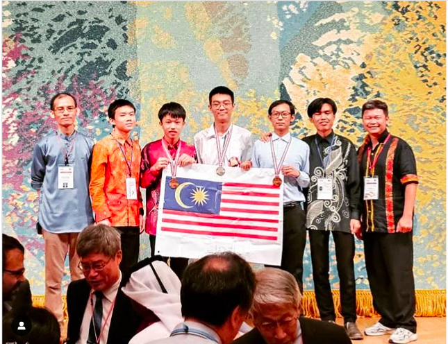 A group of people holding a flagDescription automatically generated