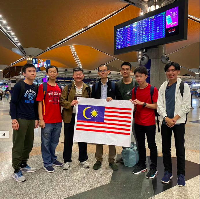 A group of people holding a flagDescription automatically generated